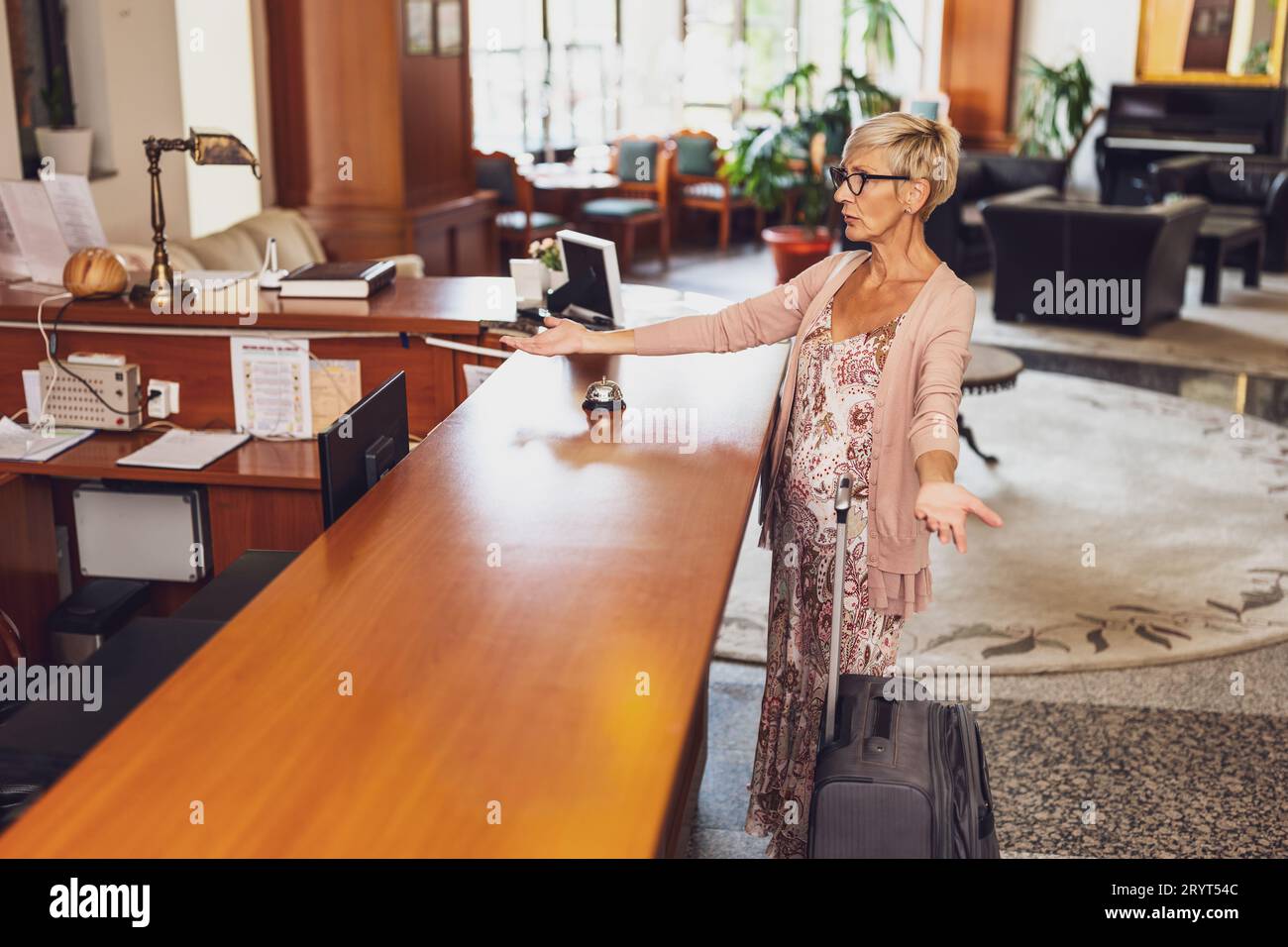 Mature woman comes to the hotel at the reception. She is tired of ...