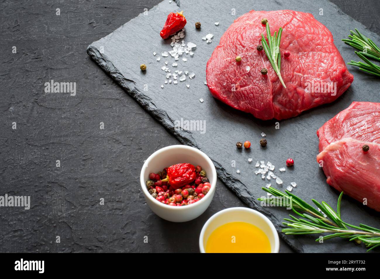 Raw meat beef steaks on black slate board, spices and ingredient Stock ...