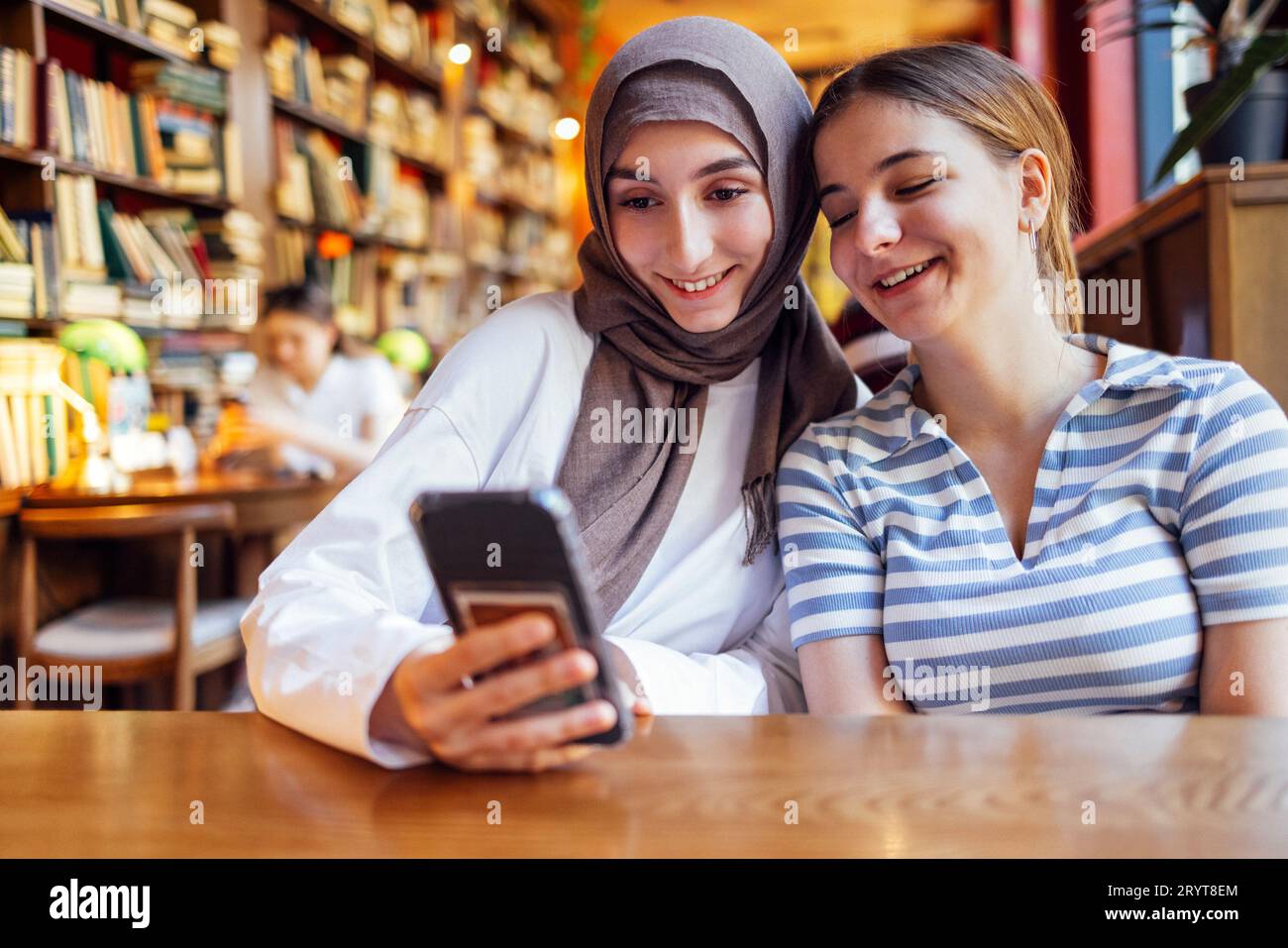 Two teenage girls of different nationalities and religions are sitting ...