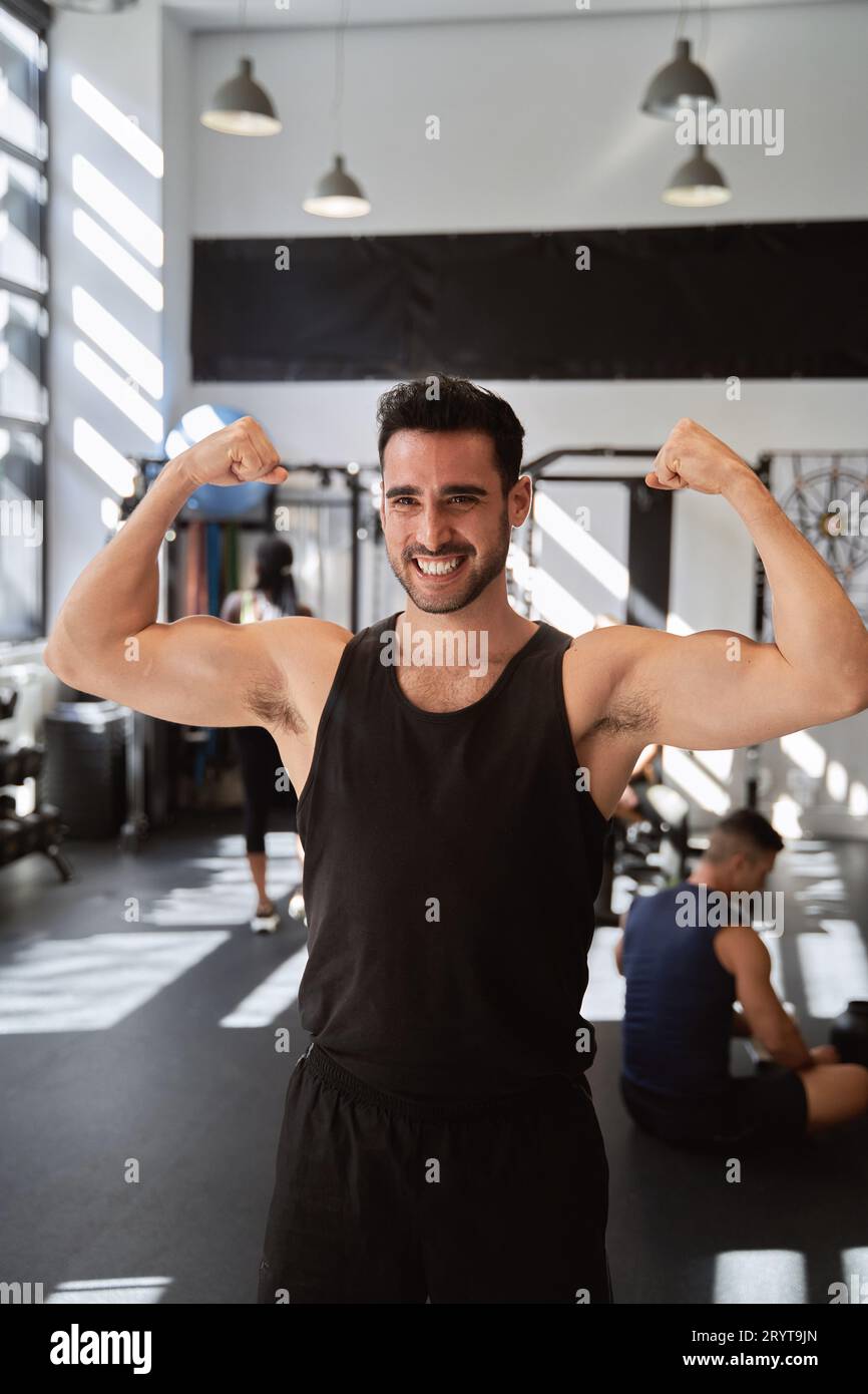 Fitness man showing his arm muscles while posing at the gym. Sports ...