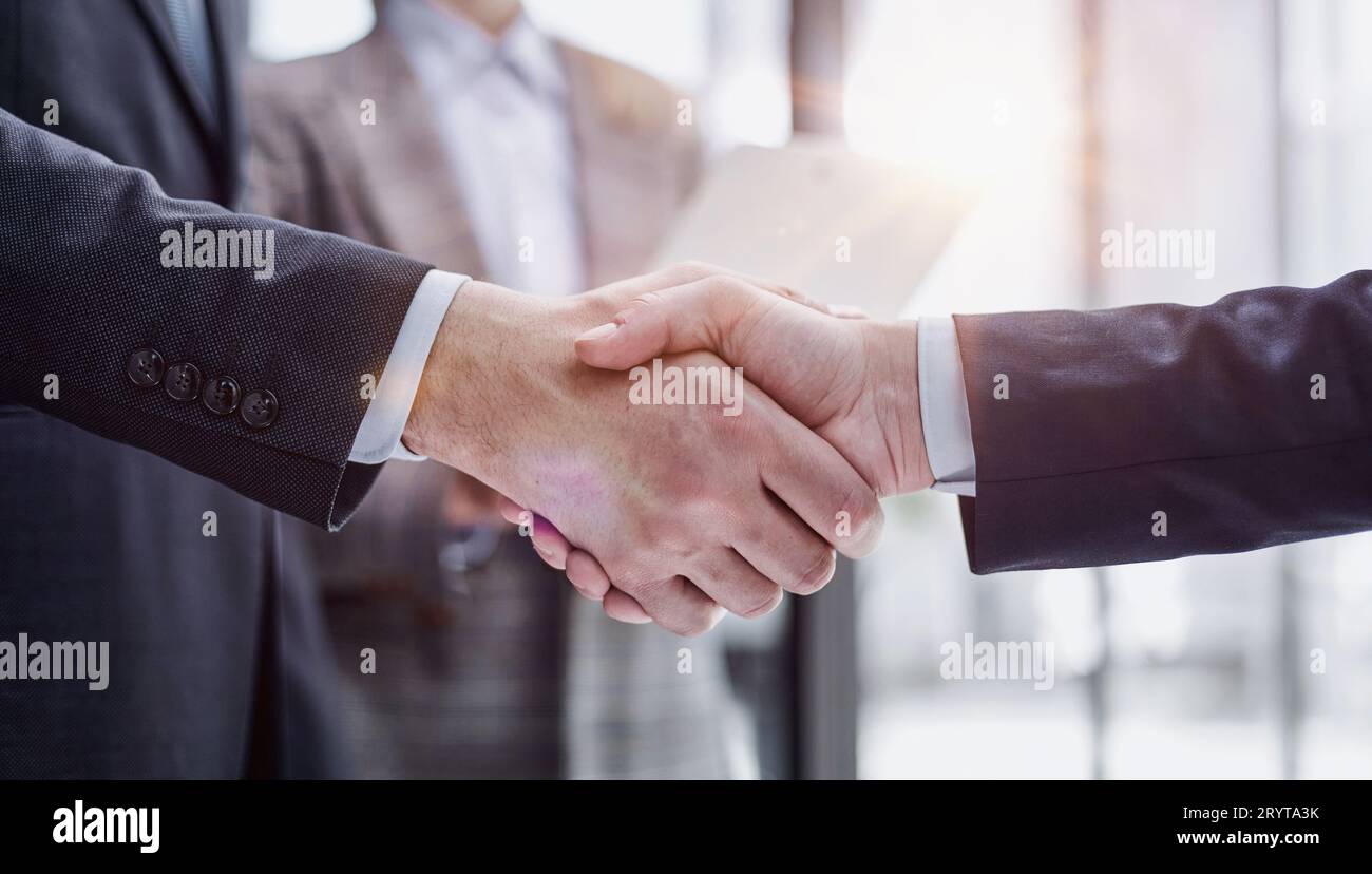 executives shaking hands in front of their manager and a colleague ...