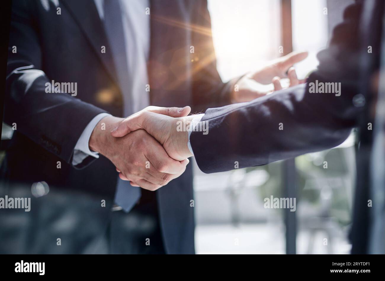 executives shaking hands in front of their manager and a colleague ...