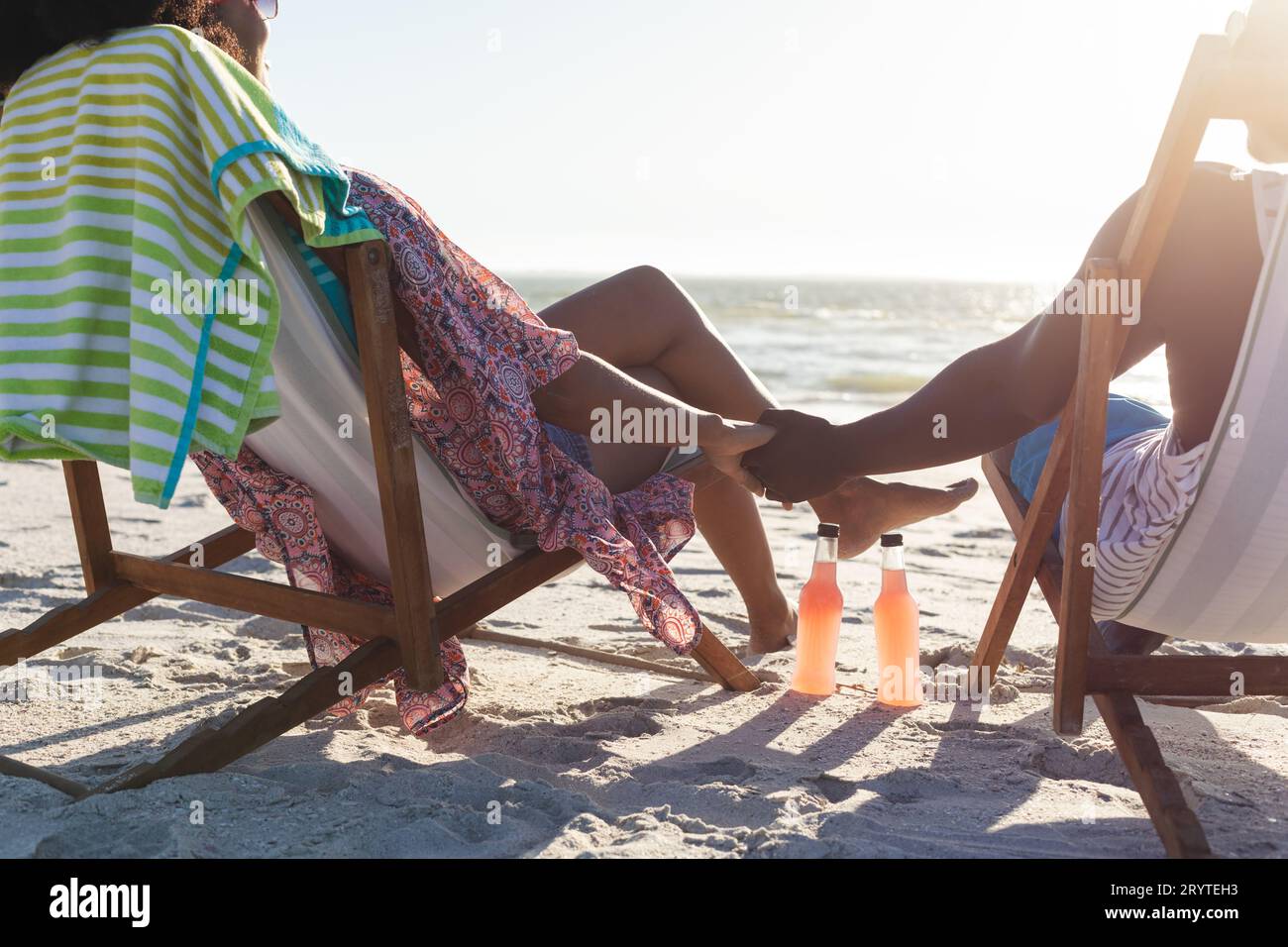 Happy African American Couple Sitting In Deckchairs Holding Hands On