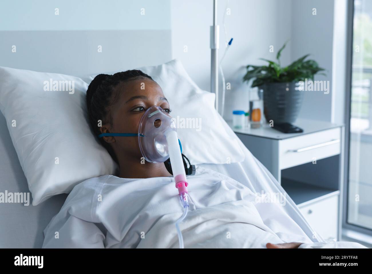 African american female patient with oxygen mask, lying on bed in ...