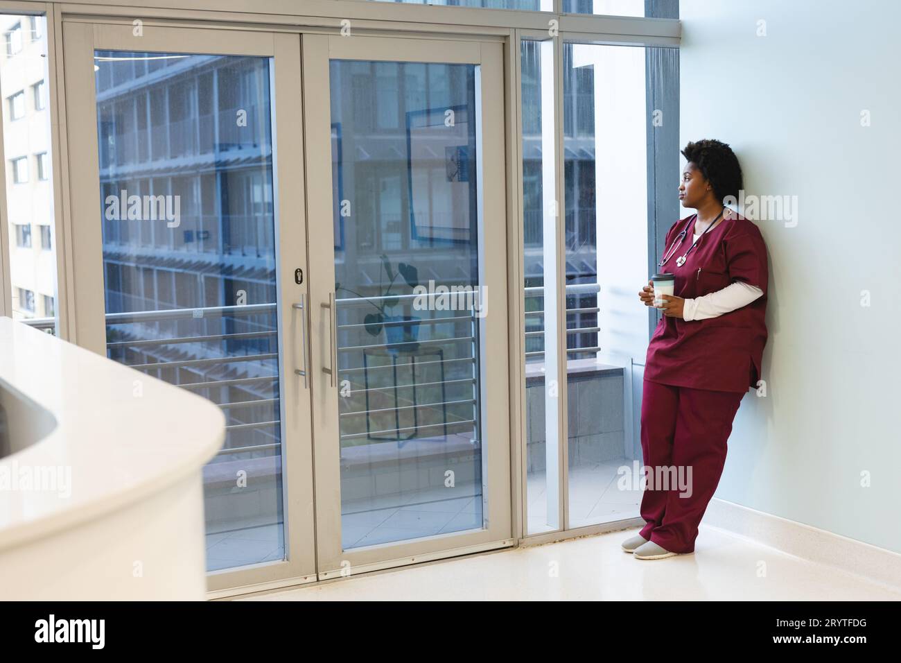 Thoughtful african american female doctor wearing scrubs, holding ...