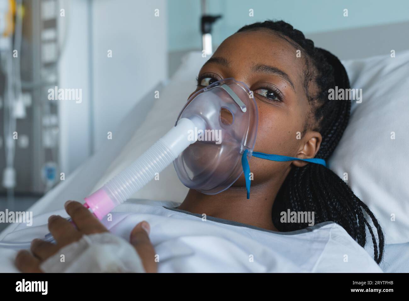 African american female patient with oxygen mask, lying on bed in ...
