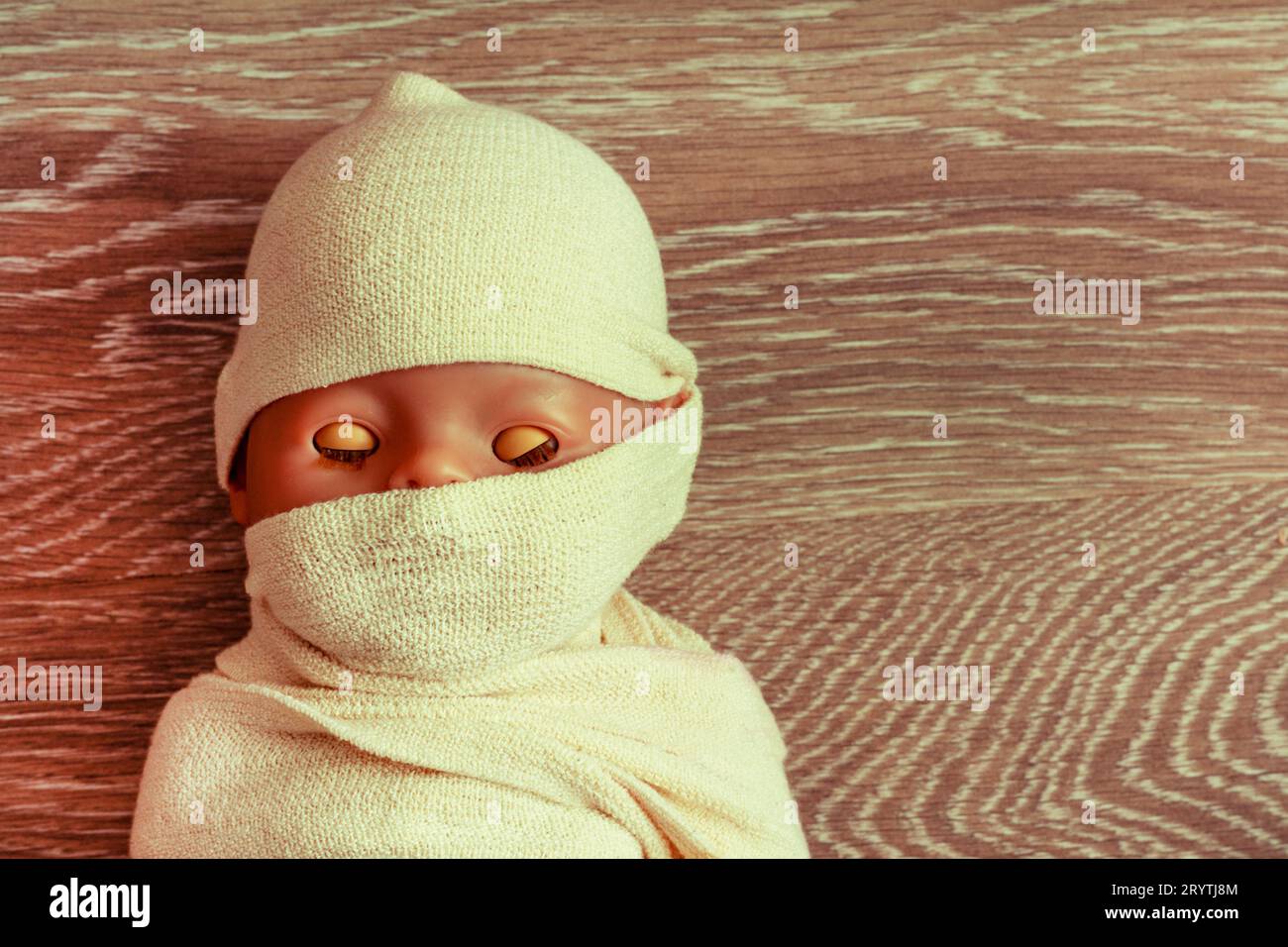 The doll the baby is wound with fabric. The body of the child is ...