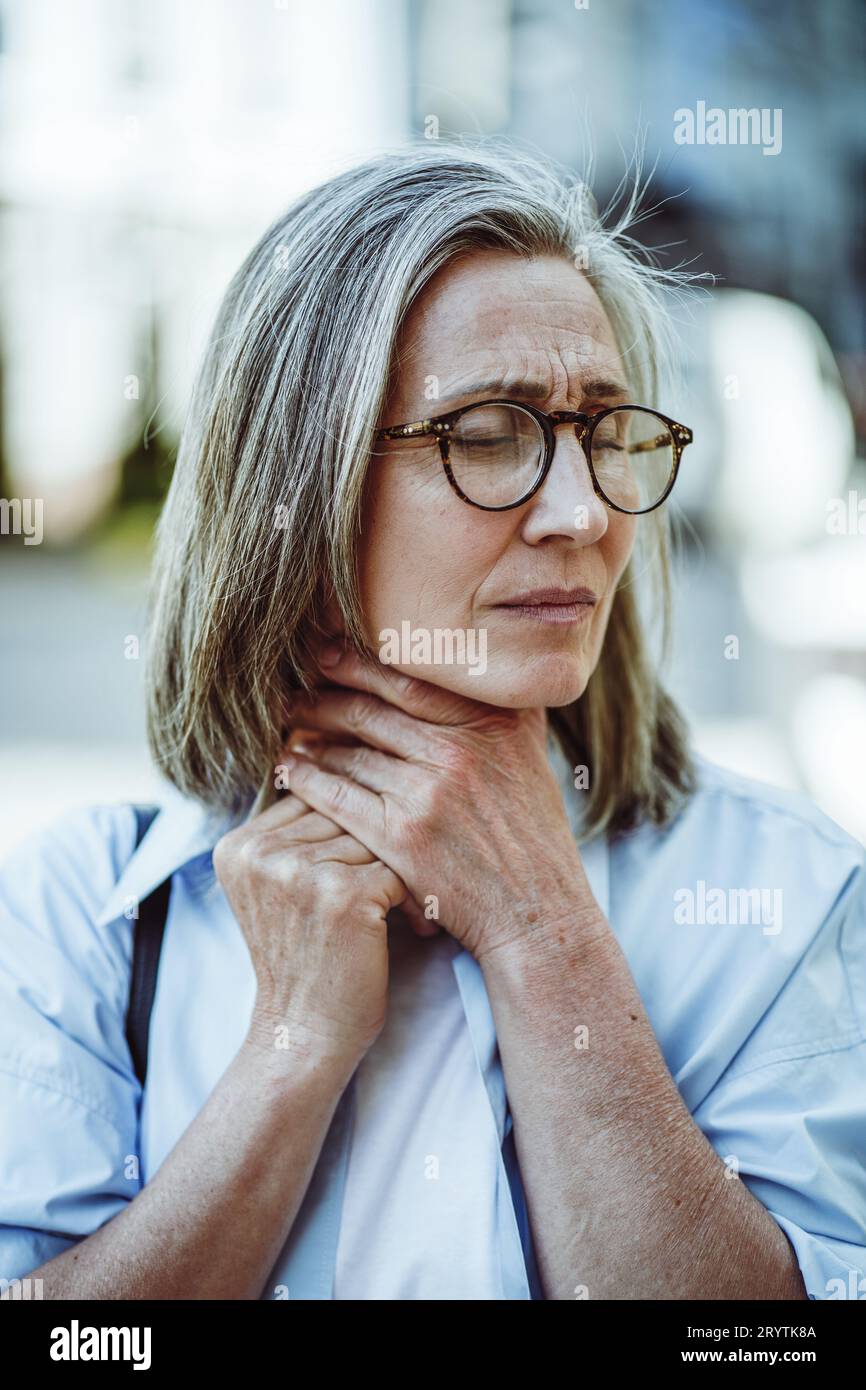 Concept of sickness through mature lady holding throat. Woman appears ...