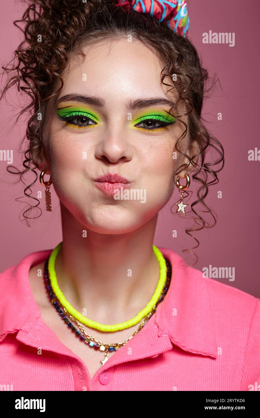 Girl puffs out her cheeks. Young smiling woman dressed in pink dress on ...