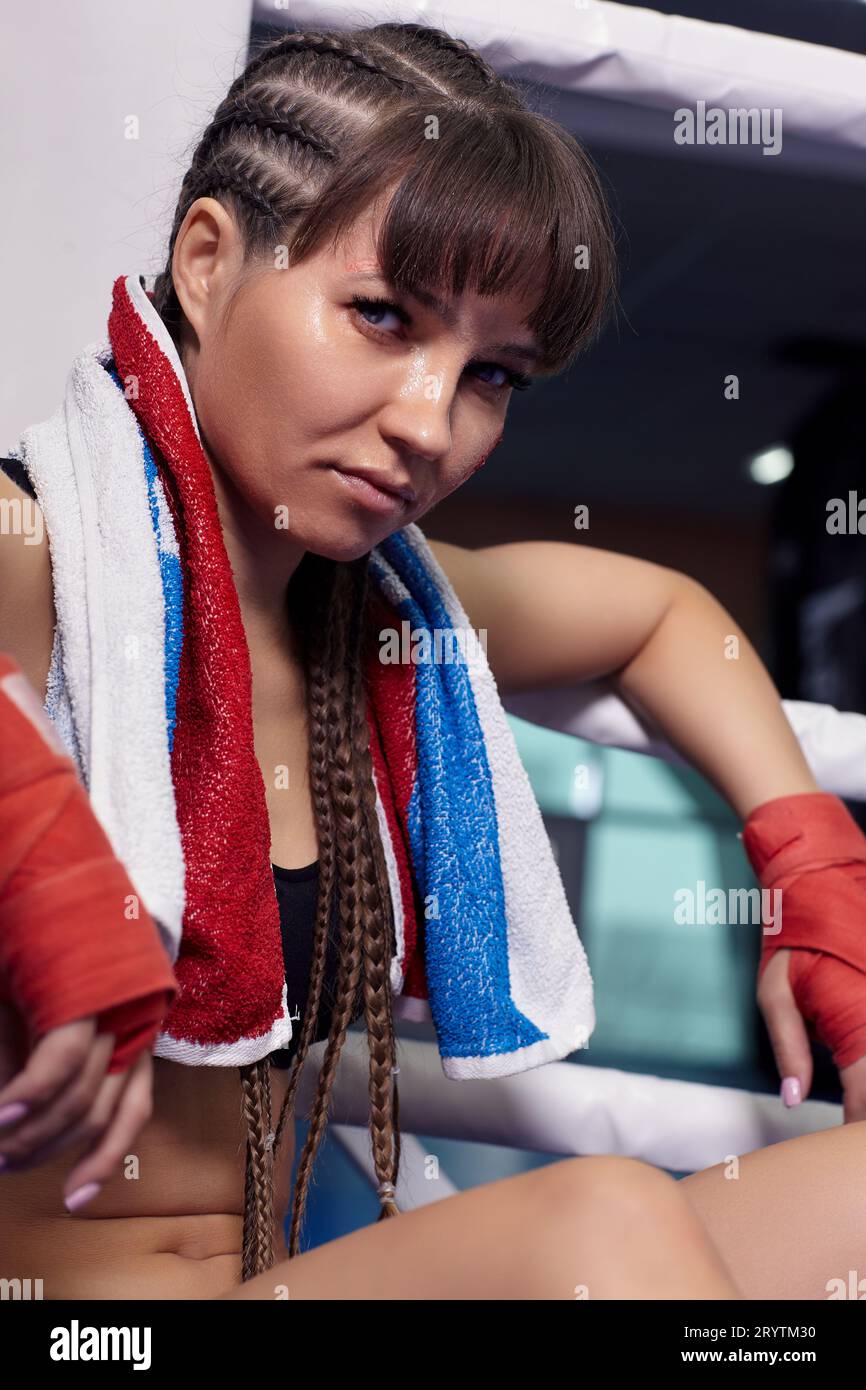 Female fighter with boxing taping bandage on her hands sits in a boxing ...