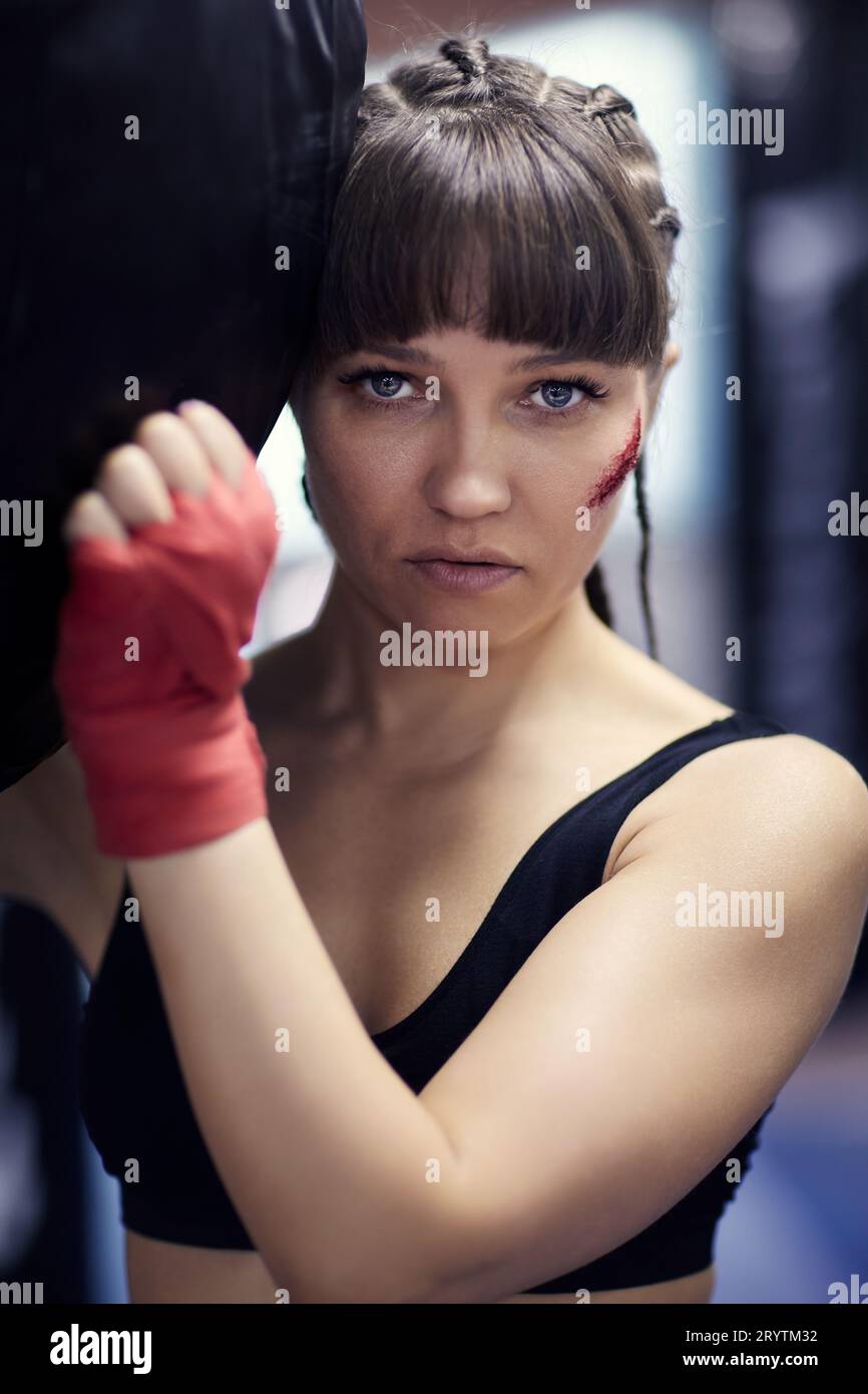 Female fighter with a boxing taping bandage on hand hugging a punching ...