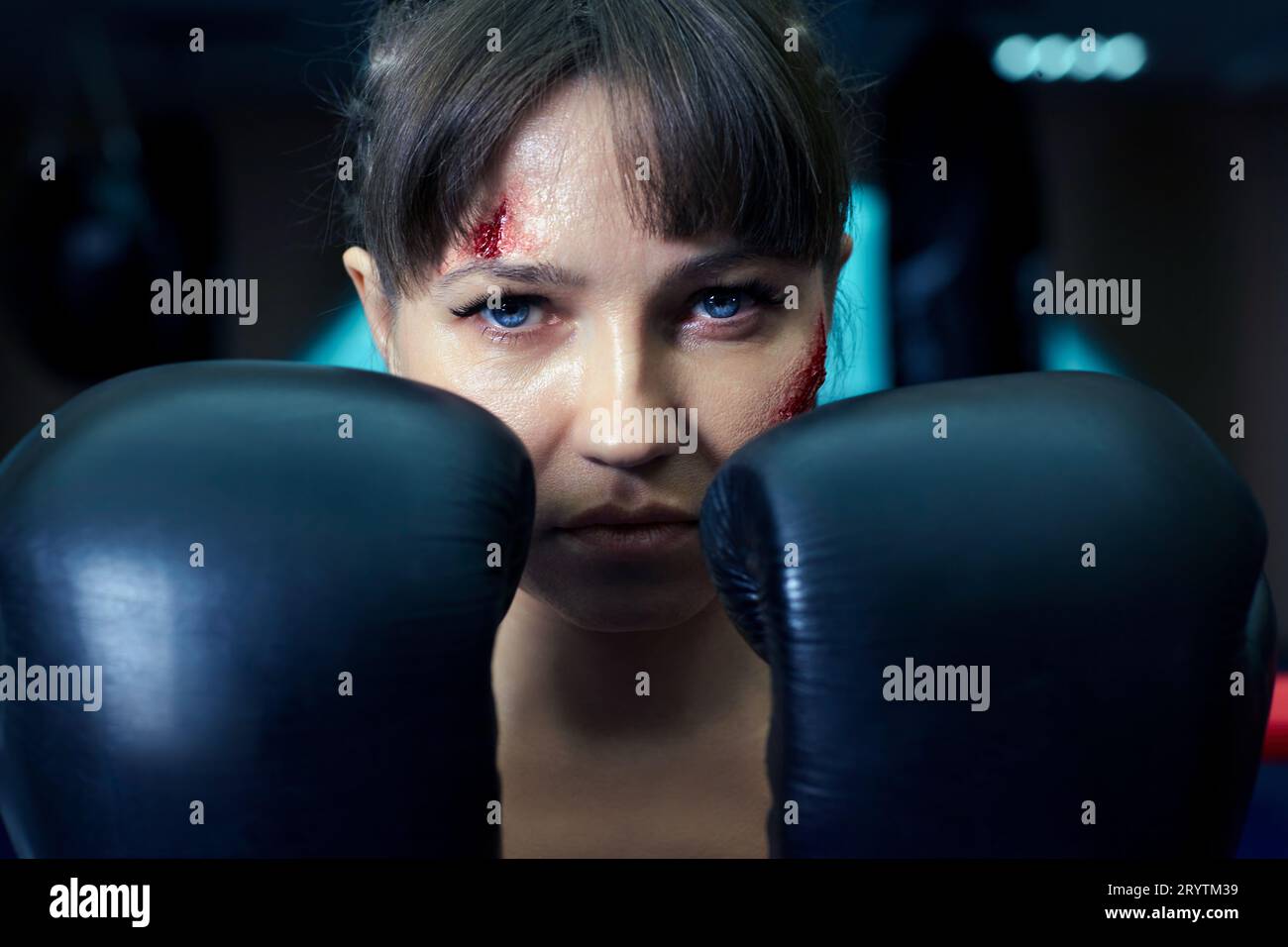 Female fighter with boxing gloves on her hands stands in a boxing ring ...