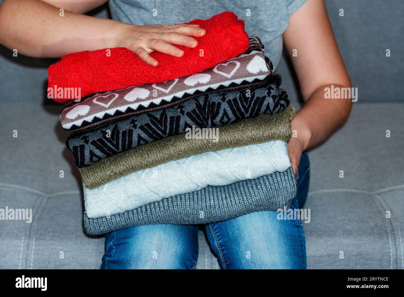 A stack of sweaters, jumpers in female hands . Girl holds hands bunch ...