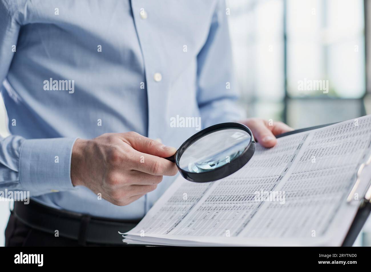 Businessman looking through a magnifying glass to documents Stock Photo ...