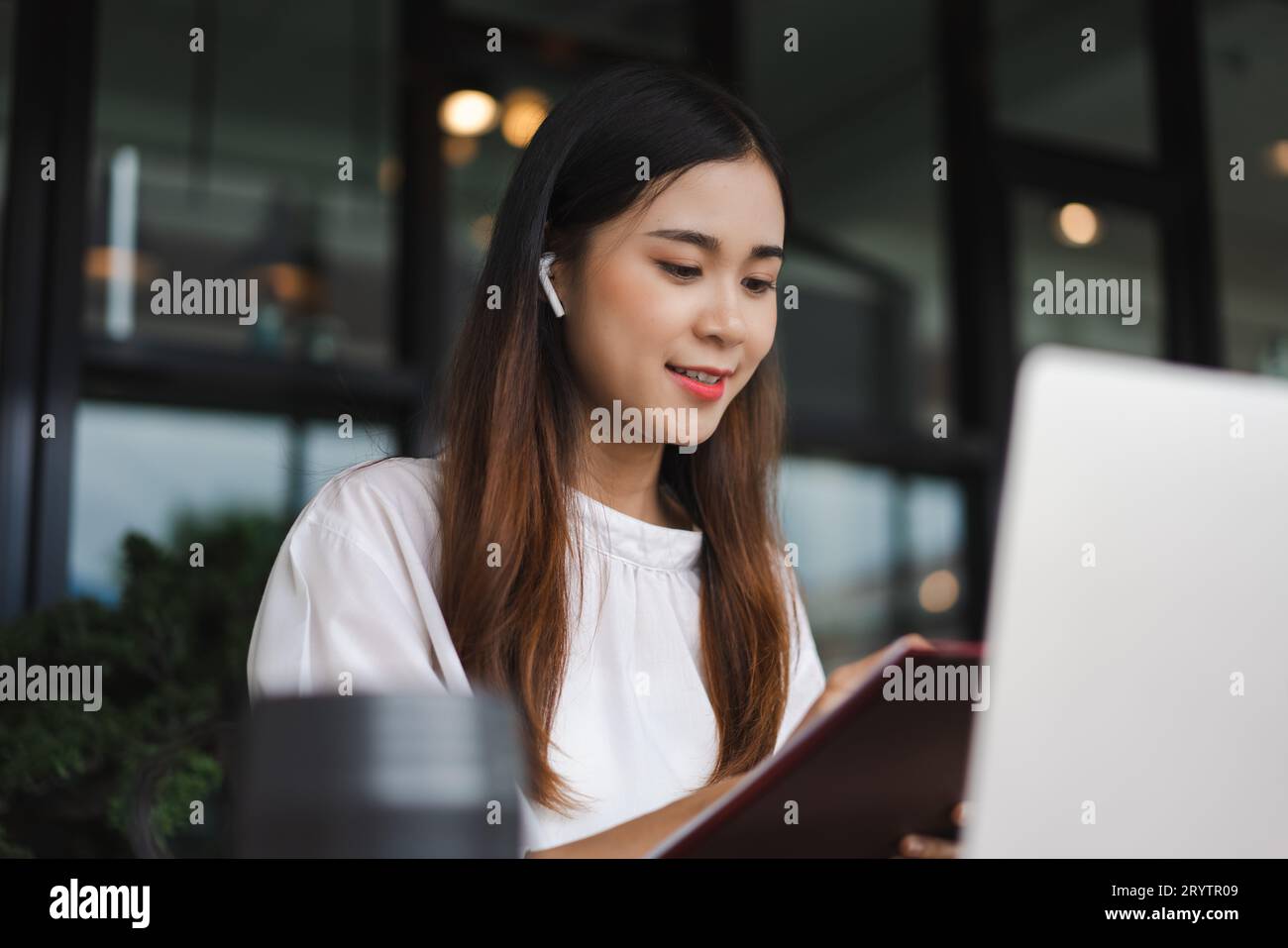 Businesswomen reading data on laptop and checking business document ...