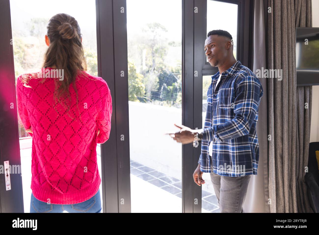 Sad diverse couple looking through window and arguing at home Stock ...