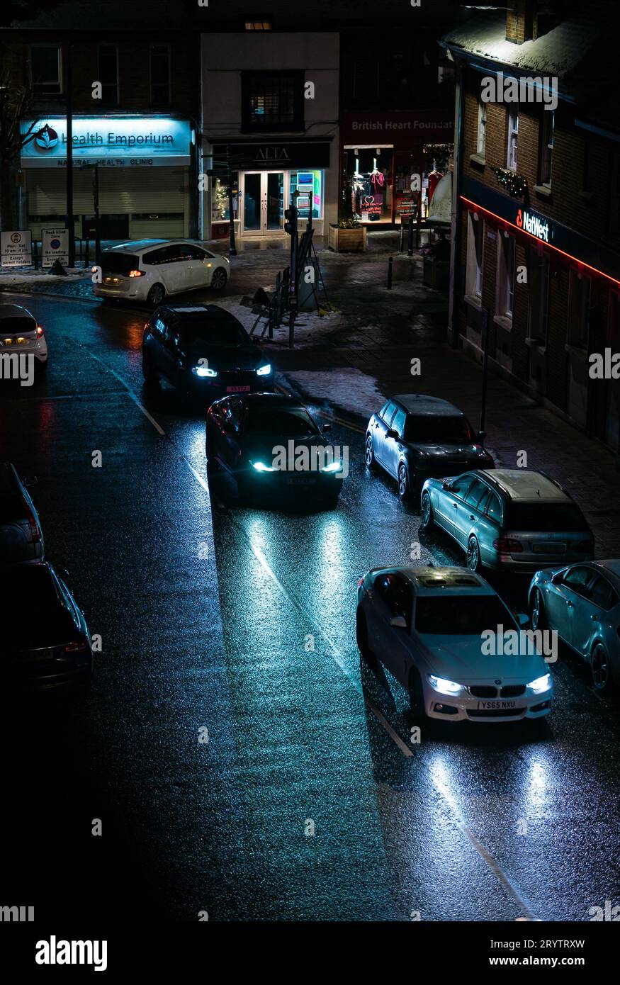 A busy city street at night, illuminated by the headlights and ...