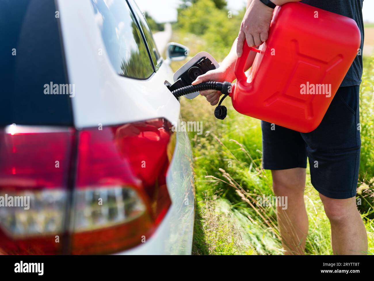 A driver refills his car's empty tank from a red canister on the side ...