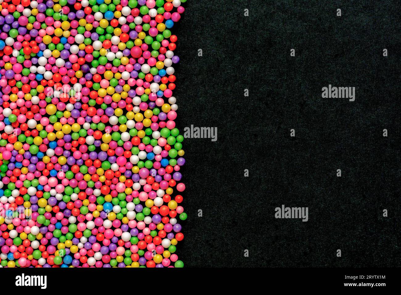 Dark, black background with colored balls. The texture is a lot of ...