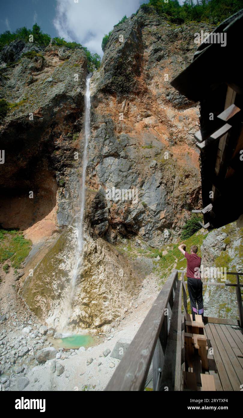 A vertical shot of a tourist taking photos of the Rinka waterfall ...