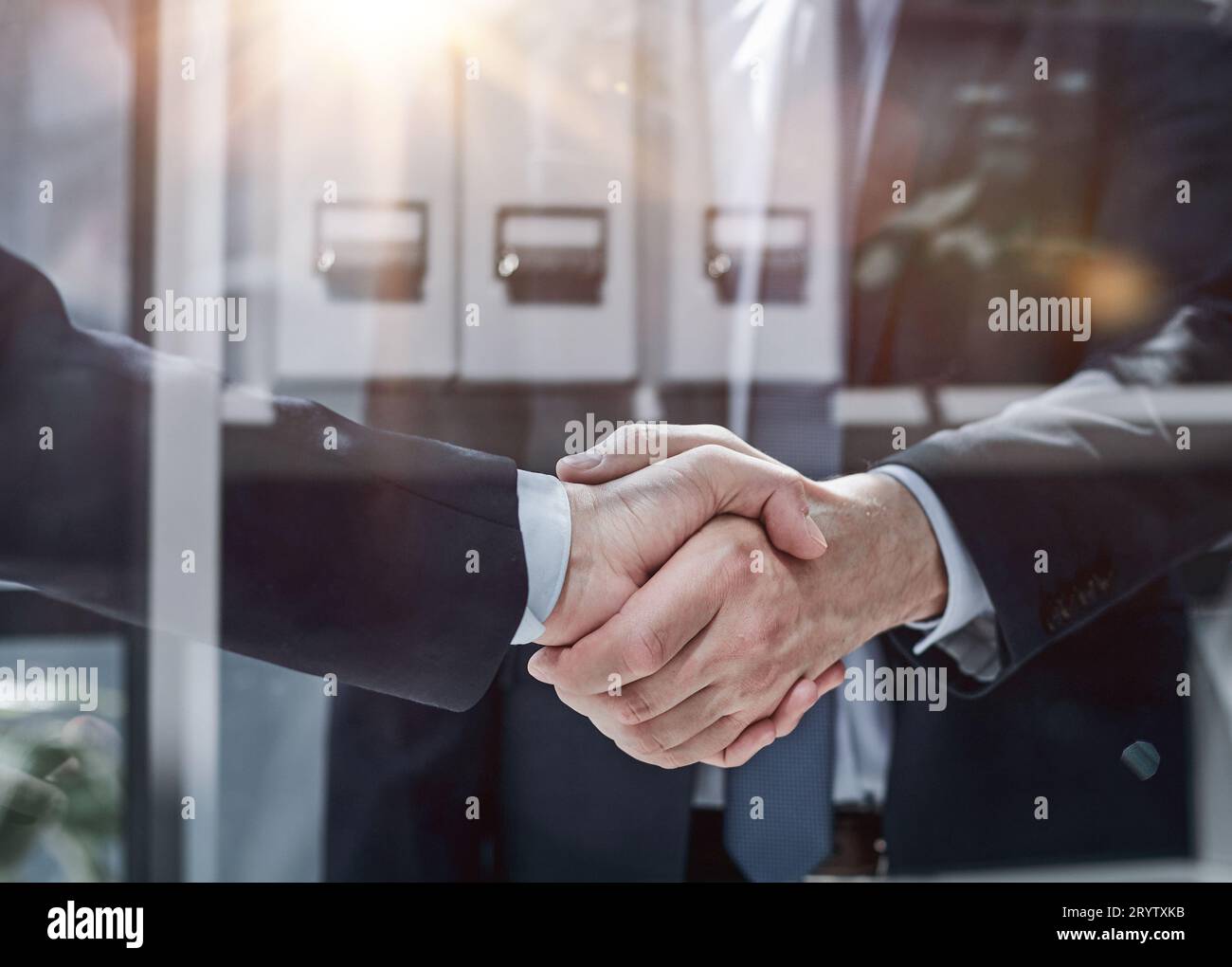 executives shaking hands in front of their manager and a colleague ...