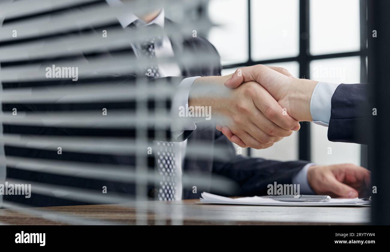 executives shaking hands in front of their manager and a colleague ...