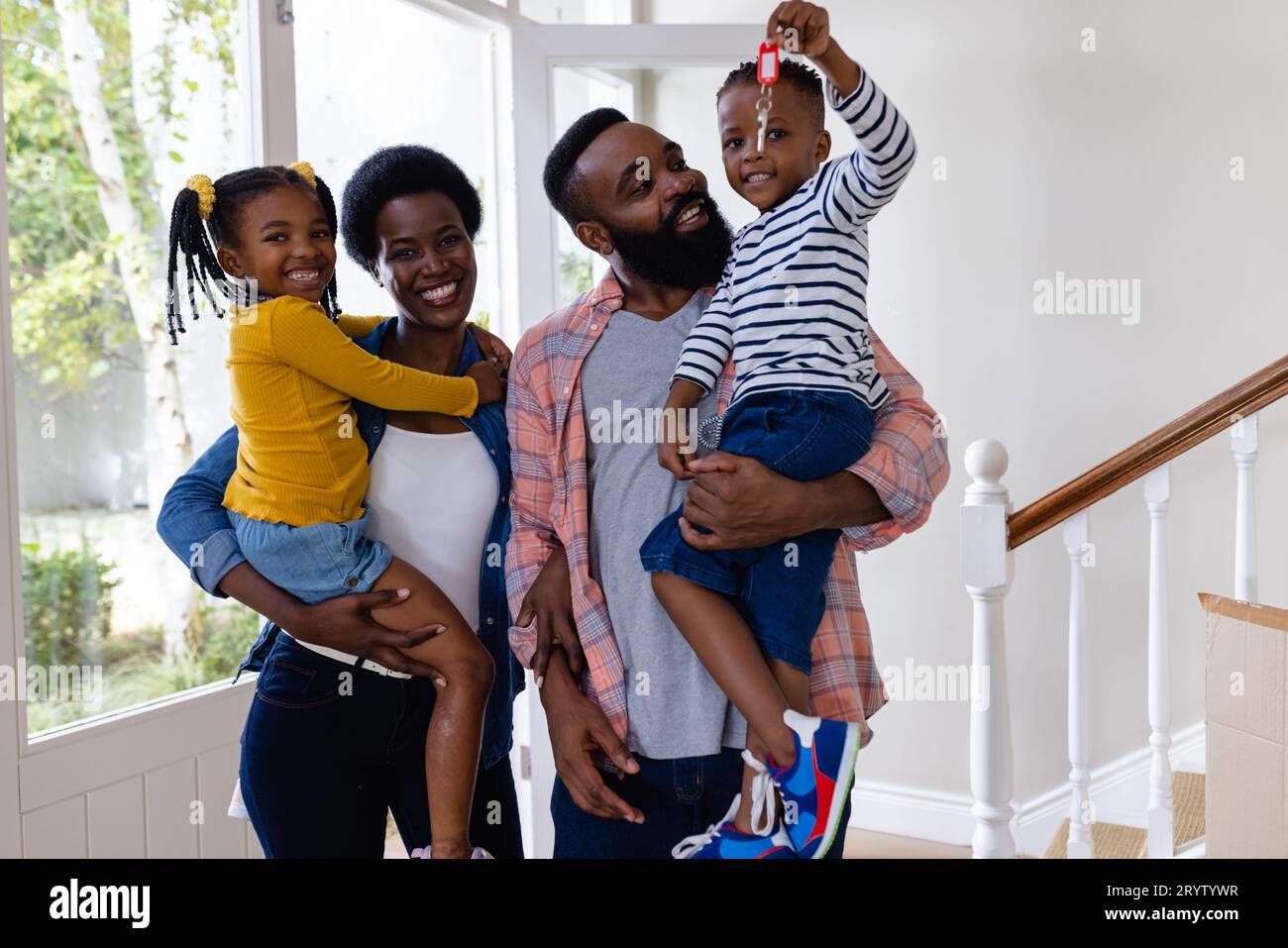 Portrait of smiling african american parents carrying children with key ...