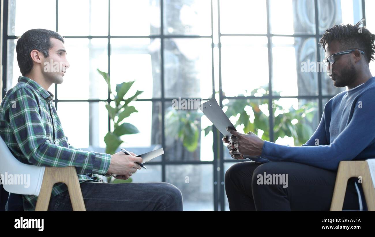 businessmen fill out a questionnaire while sitting side by side in a ...