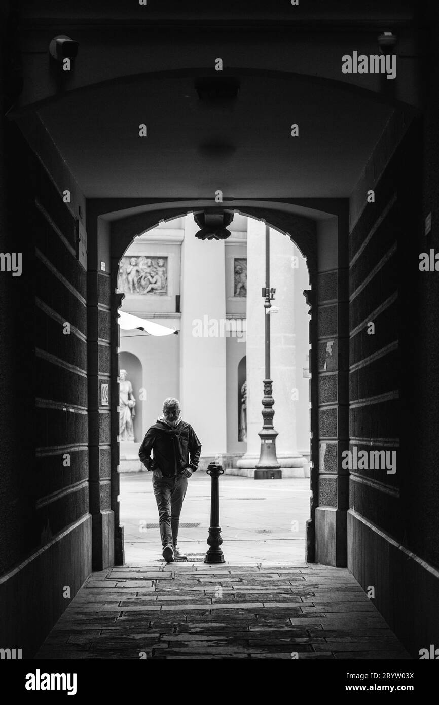 one pedestrian walking through a sheltered walkway, historic ...