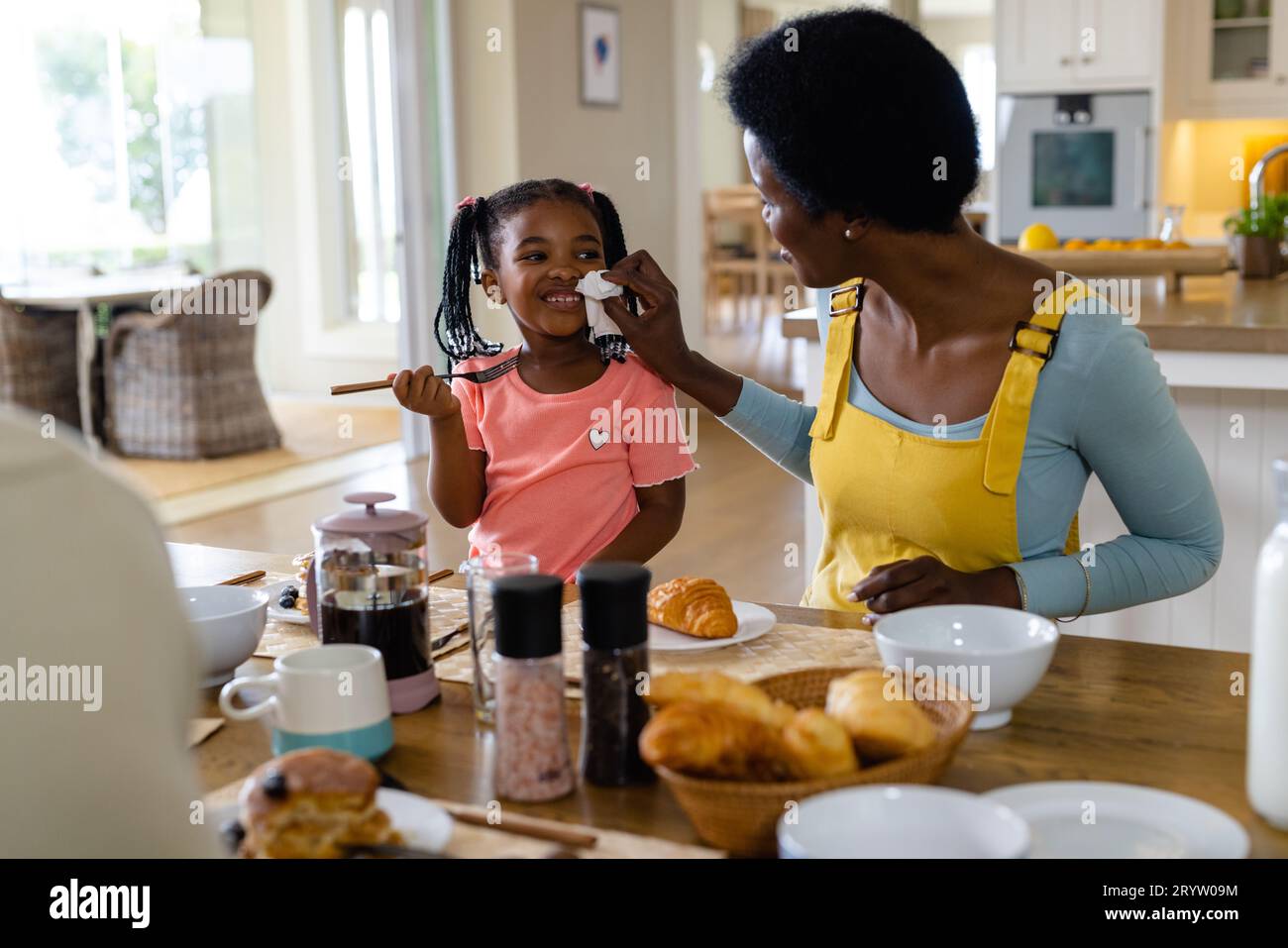 African american mother cleaning daughter's face with tissue paper ...