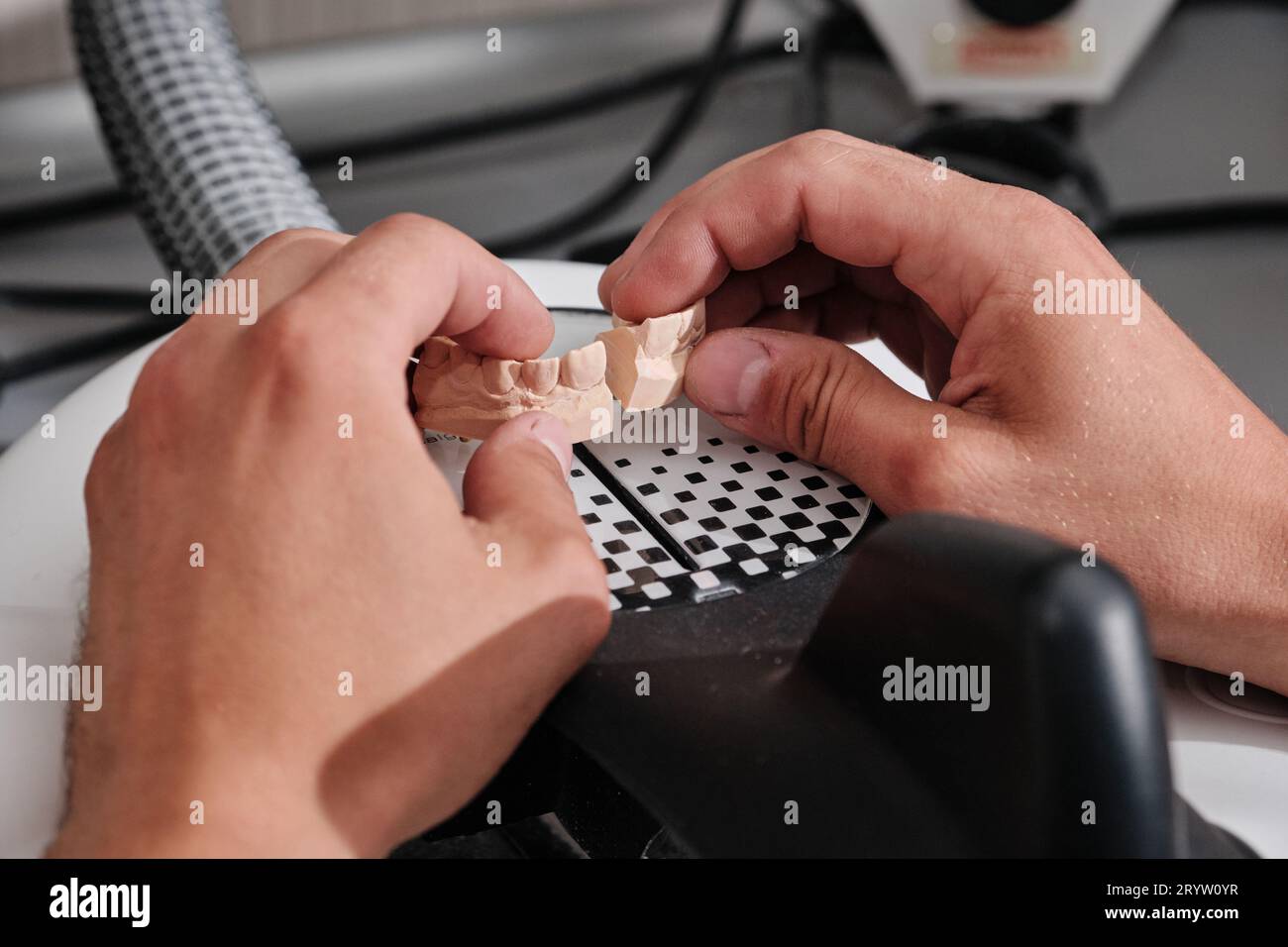 Dental technician trimming excess material from plaster models. Dental ...