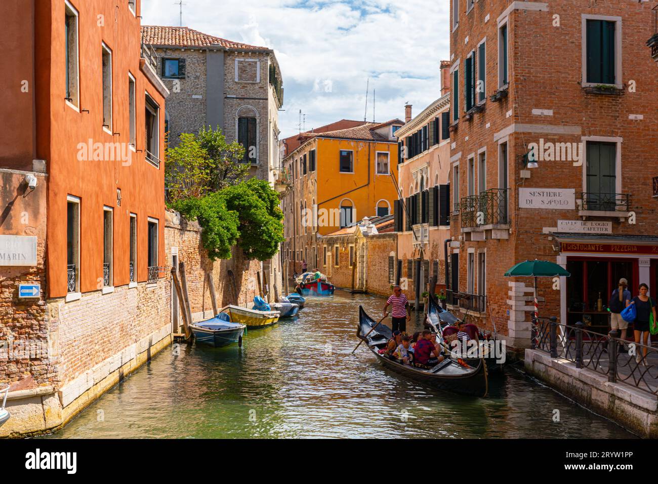 A bustling waterway between houses and buildings with small boats ...