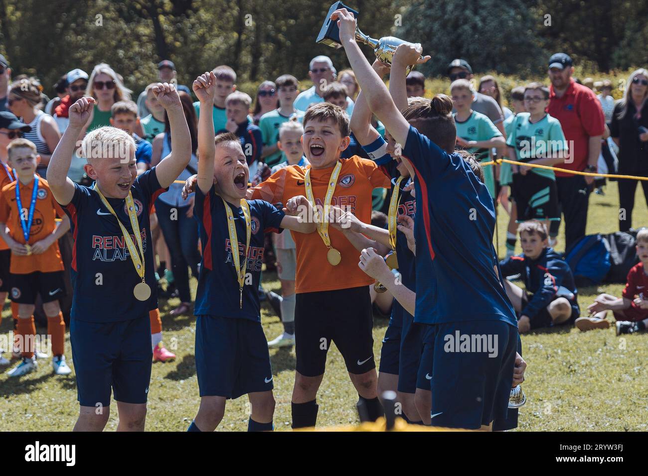 A group of children standing in celebration holding a medals above ...