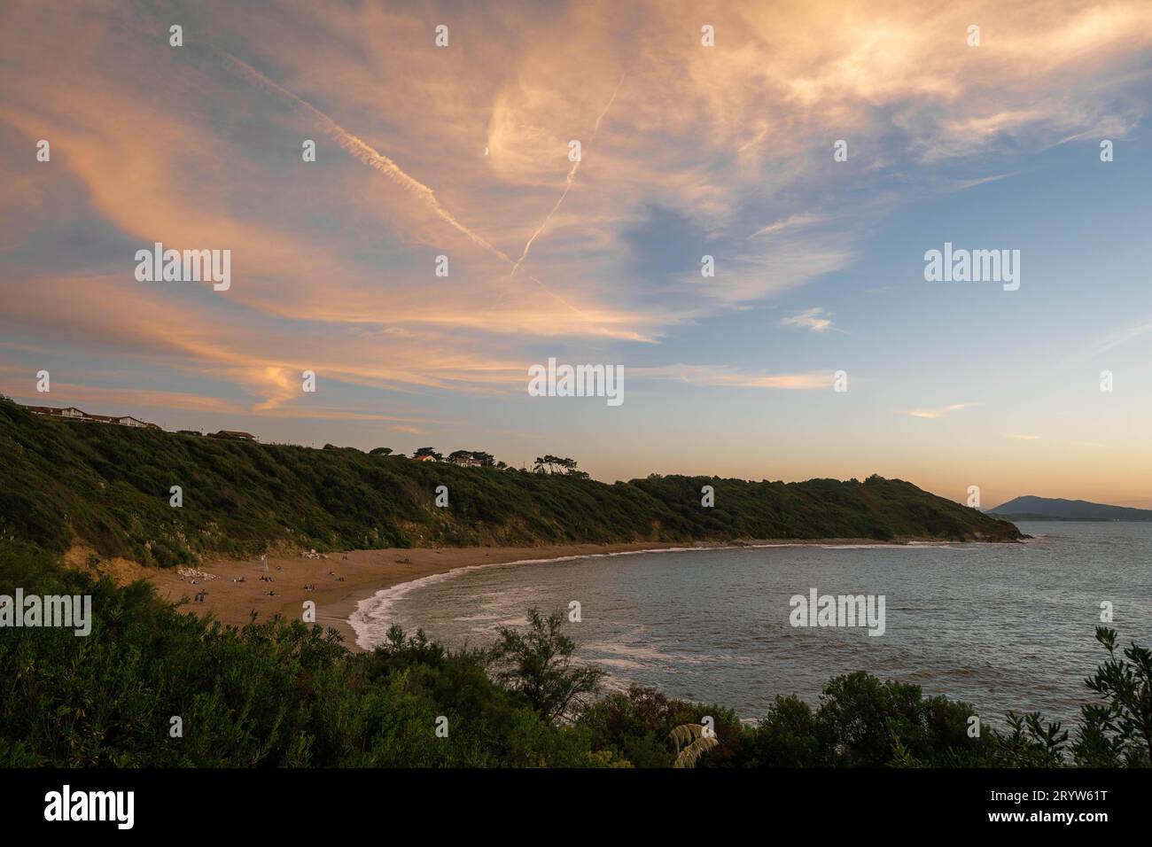 A scenic beach landscape featuring a shoreline of large, jagged rocks ...