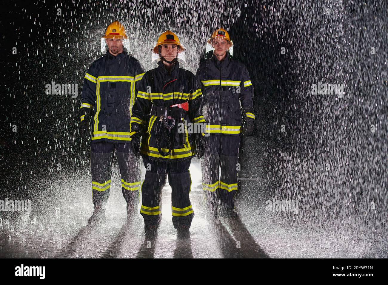 A group of professional firefighters marching through the rainy night ...