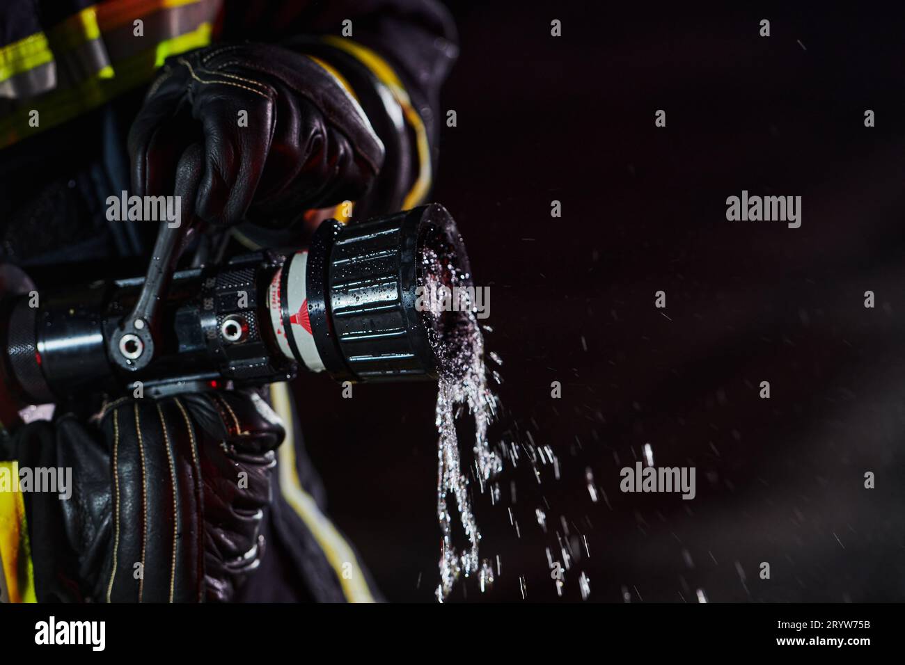 Firefighter using a water hose to eliminate a fire hazard. Team of ...