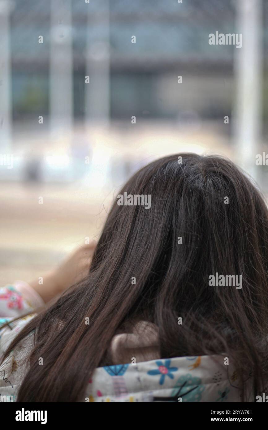 A solitary individual looking out a window in contemplation, with a ...