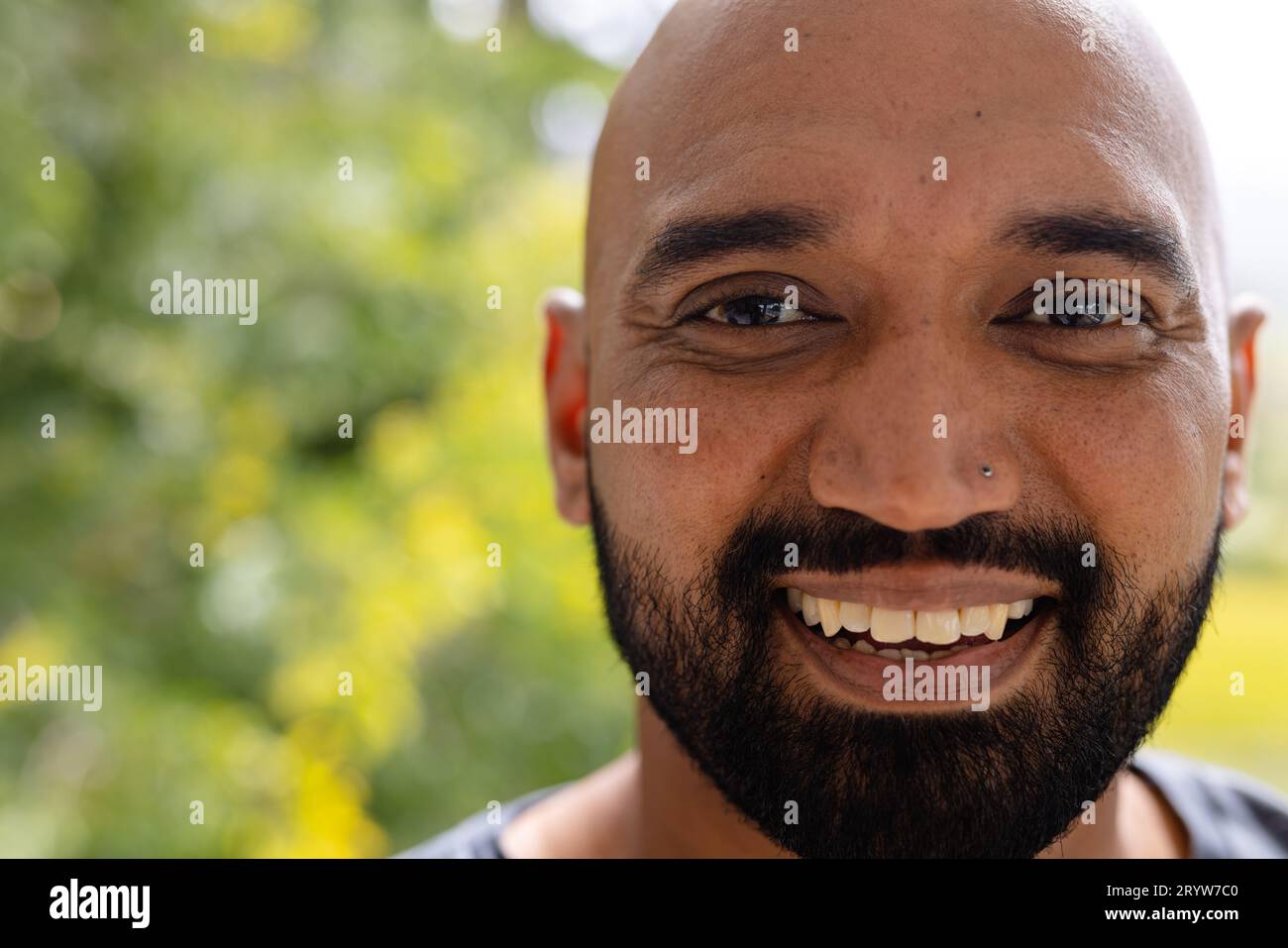 Half portrait of smiling bald biracial man with beard in front of ...