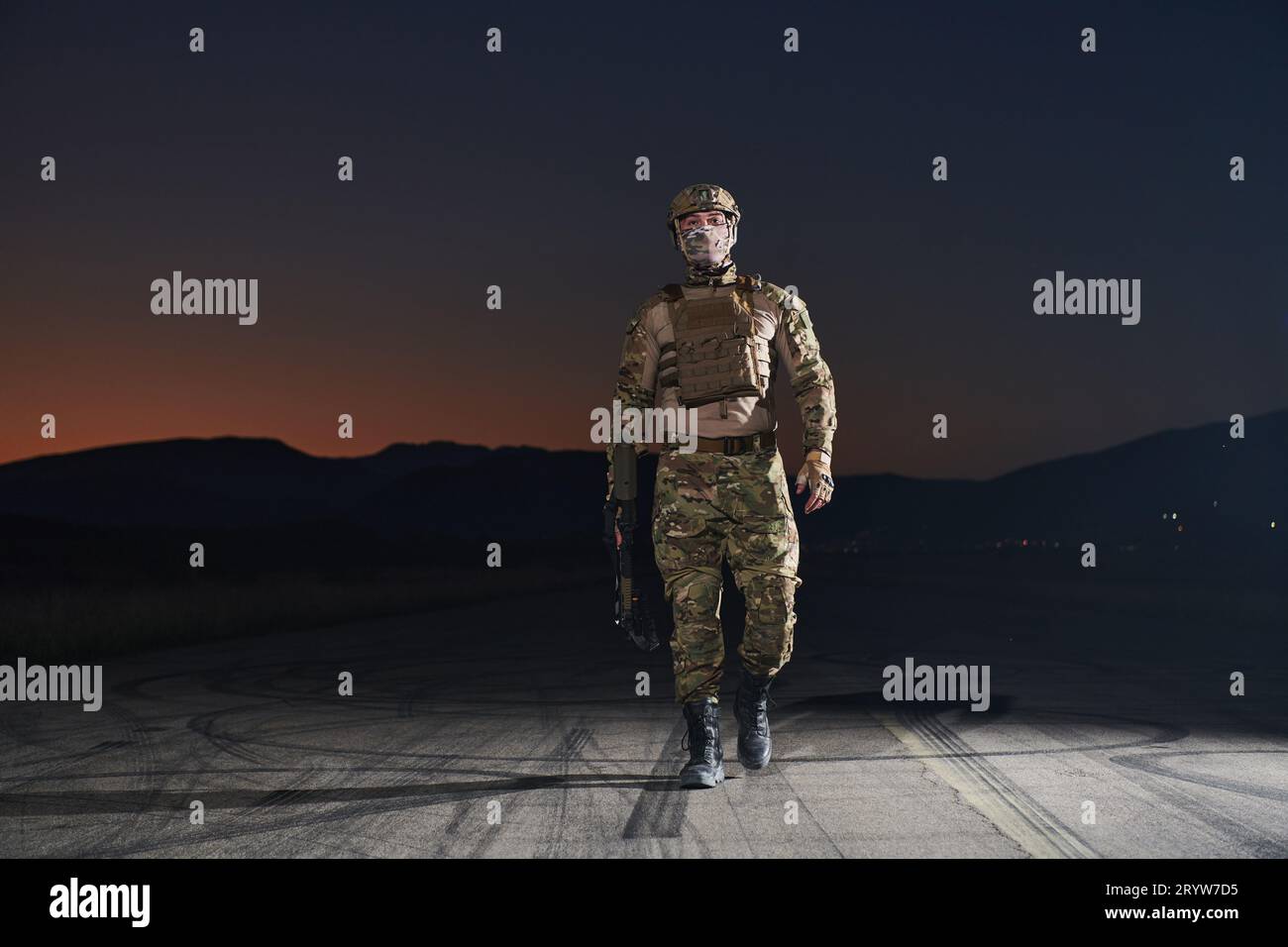 A professional soldier in full military gear striding through the dark ...