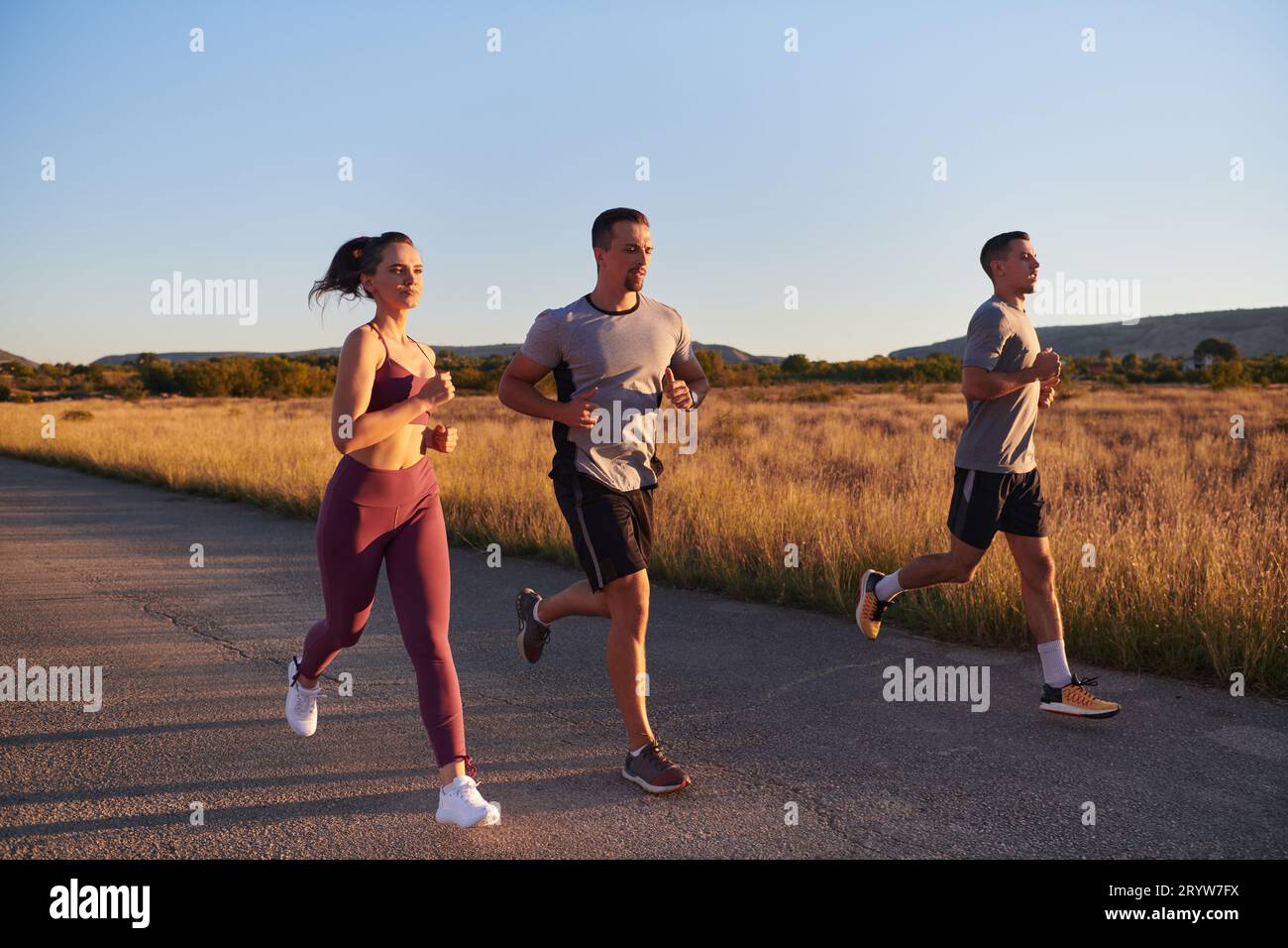 A group of young athletes running together in the early morning light ...