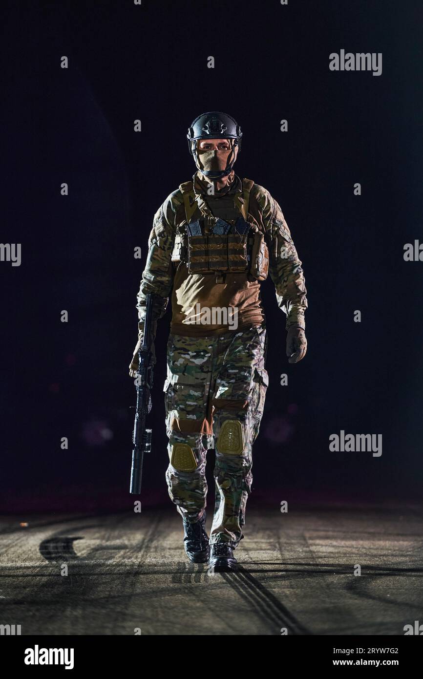 A professional soldier in full military gear striding through the dark ...