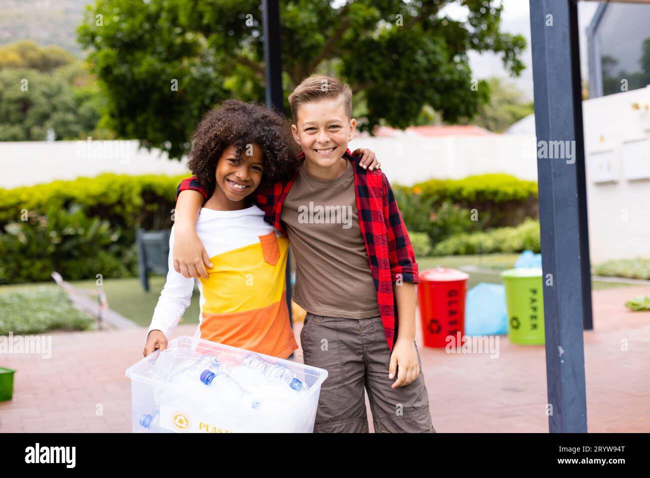 Portrait of two happy diverse schoolboys cleaning and recycling waste ...