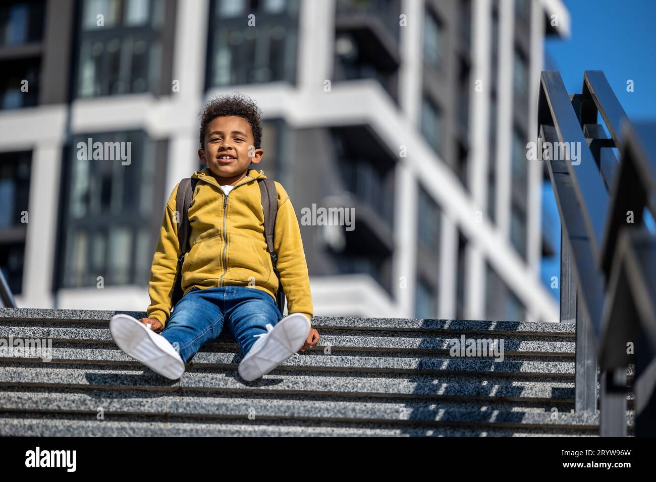 Cute schoolboy sitting on the steps and resting Stock Photo - Alamy
