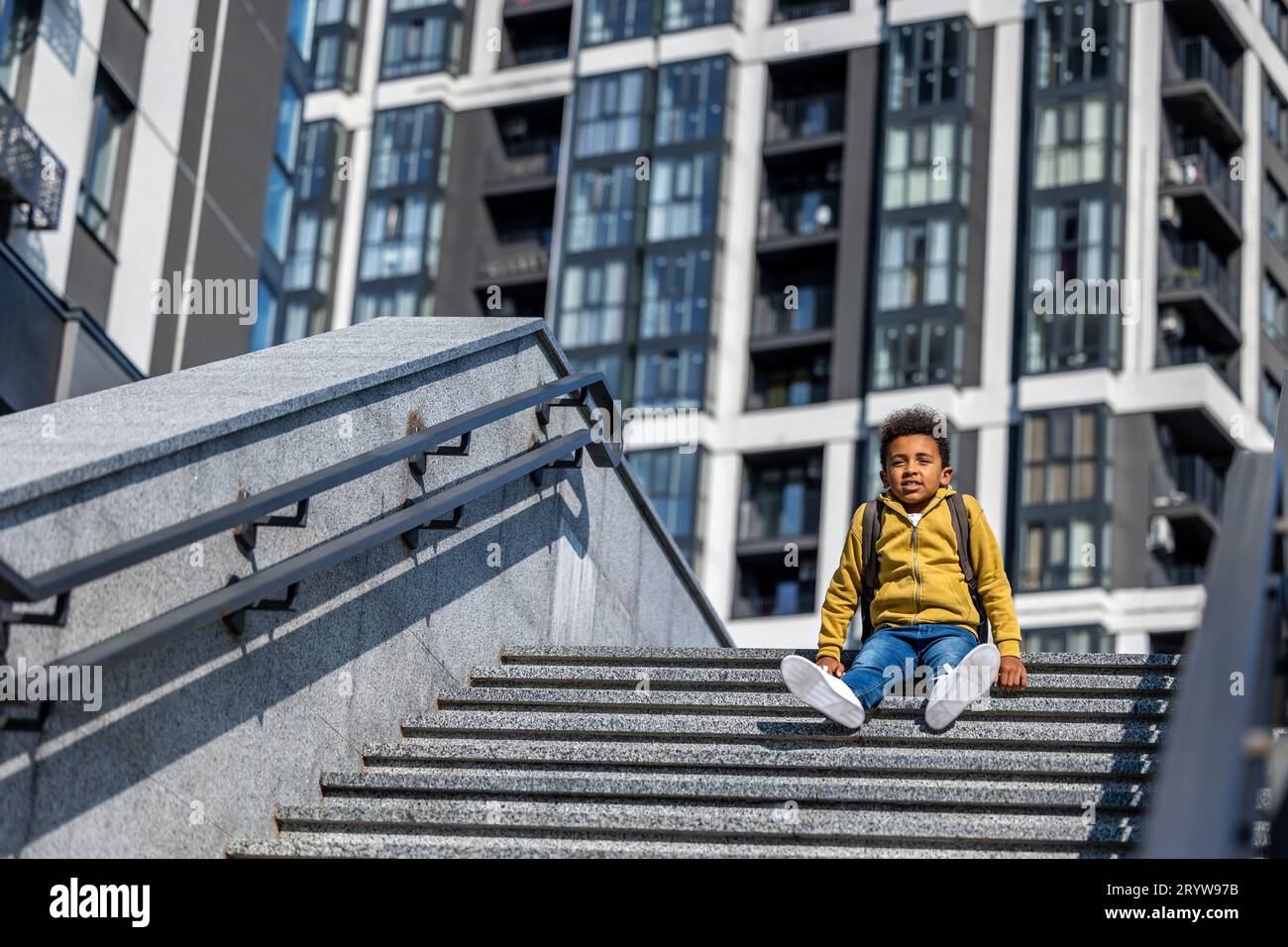 Cute schoolboy sitting on the steps and resting Stock Photo - Alamy