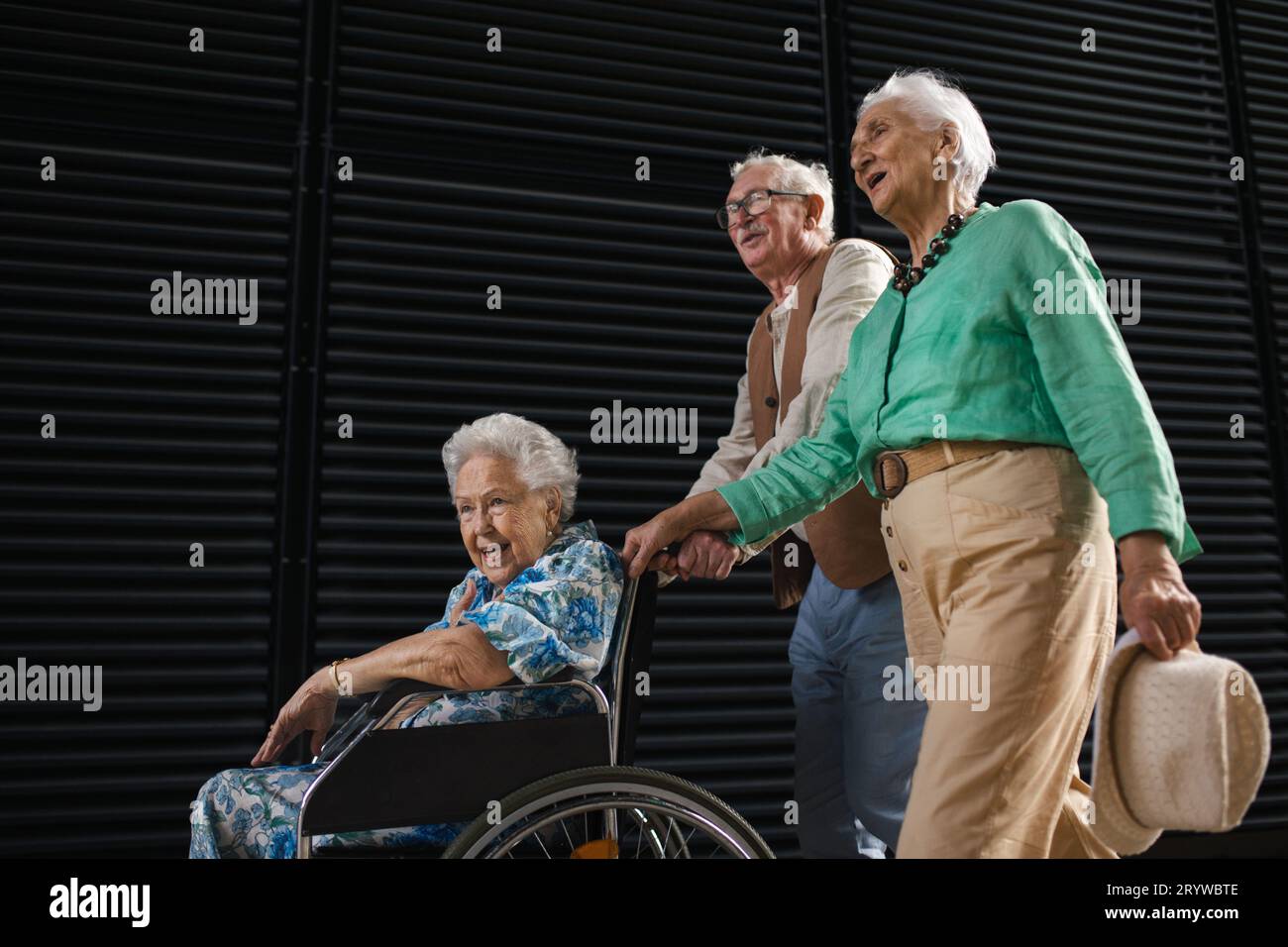 Elderly friends pushing senior woman in wheelchair Stock Photo - Alamy