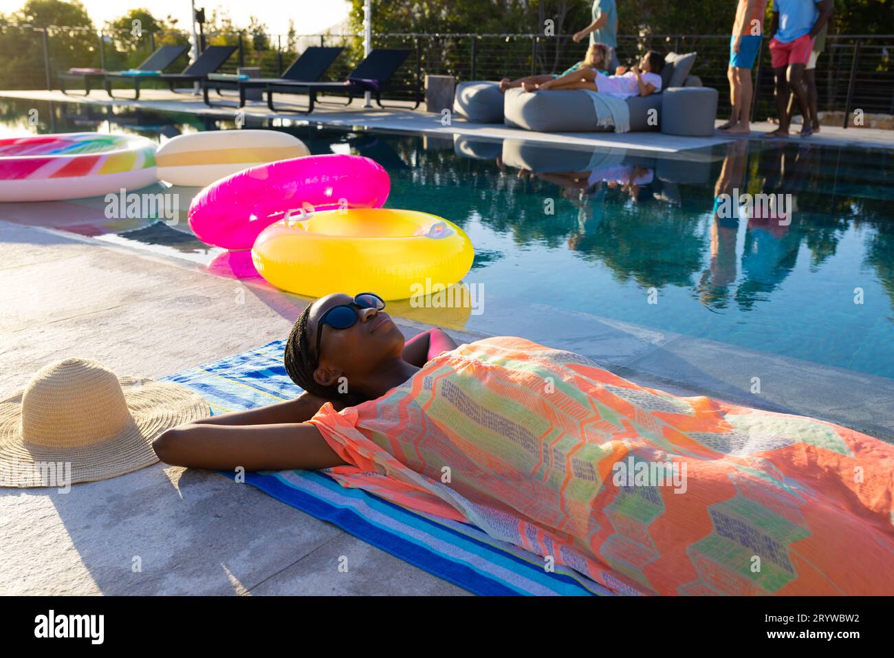 Happy african american woman lying on towel and sunbathing next to ...