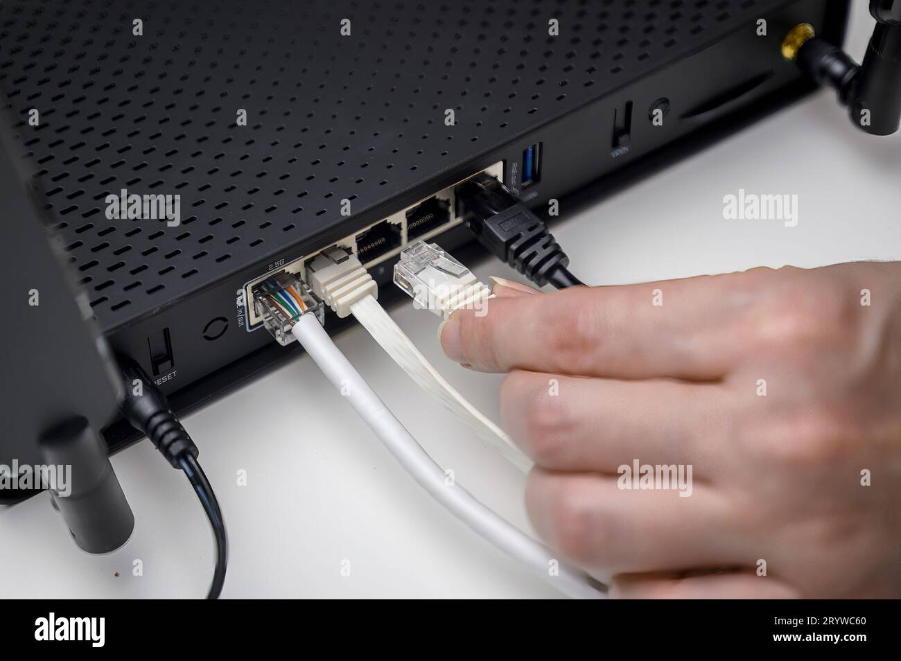 a close up of a person plugging wires into a router. A person connects ...