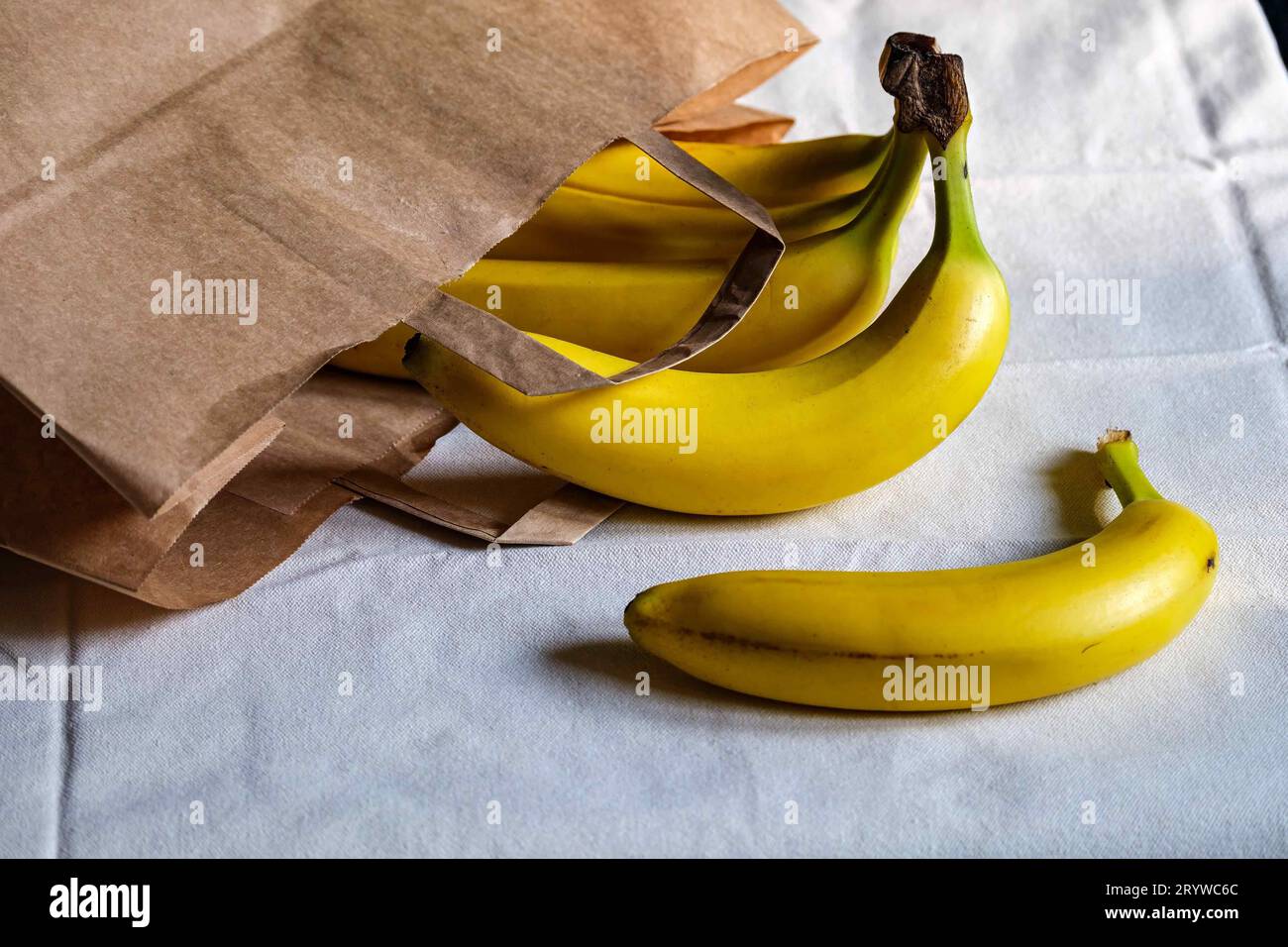 bananas in a paper bag lie on the table. bananas in the kitchen Stock ...