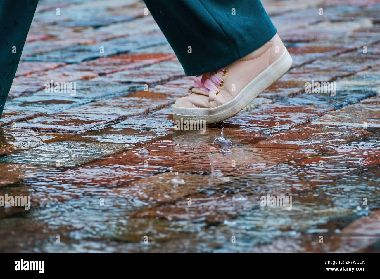 walking through a puddle in the rain. a passerby's foot on the paving ...