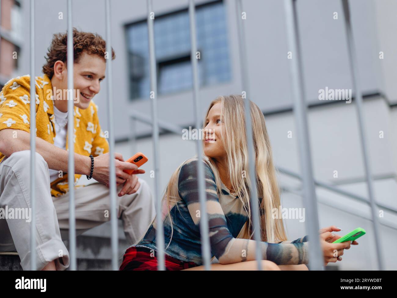 Young Gen Z students meeting outside in the city, sitting on the stairs ...